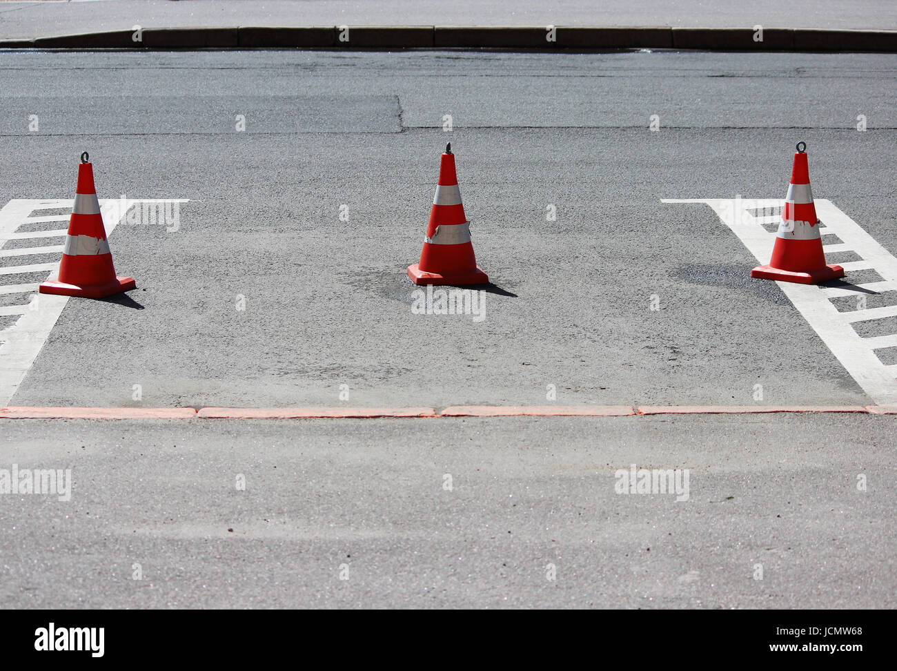 plastic signaling traffic cones encloses a place in the parking lot for ...