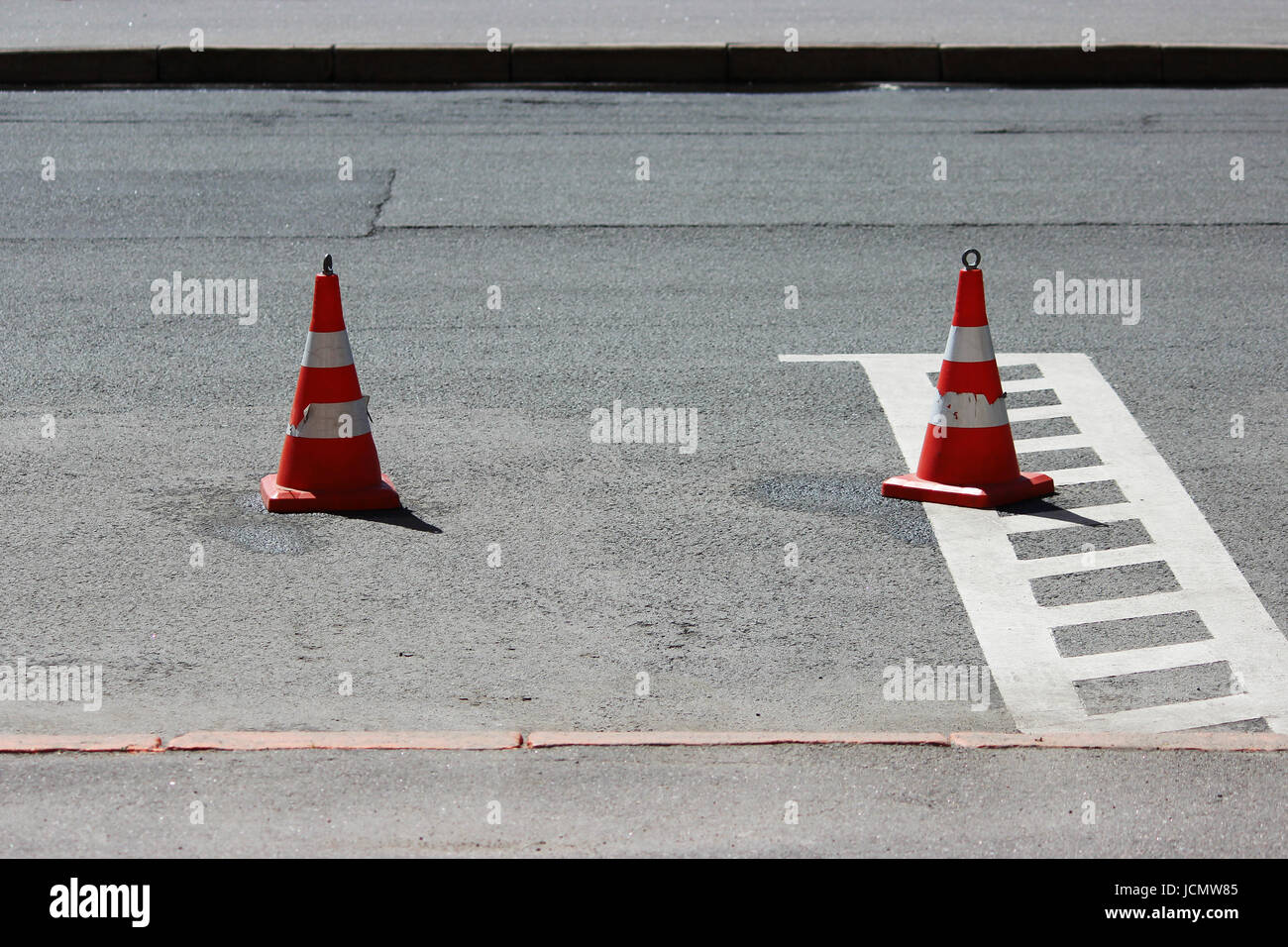 plastic signaling traffic cones encloses a place in the parking lot for ...
