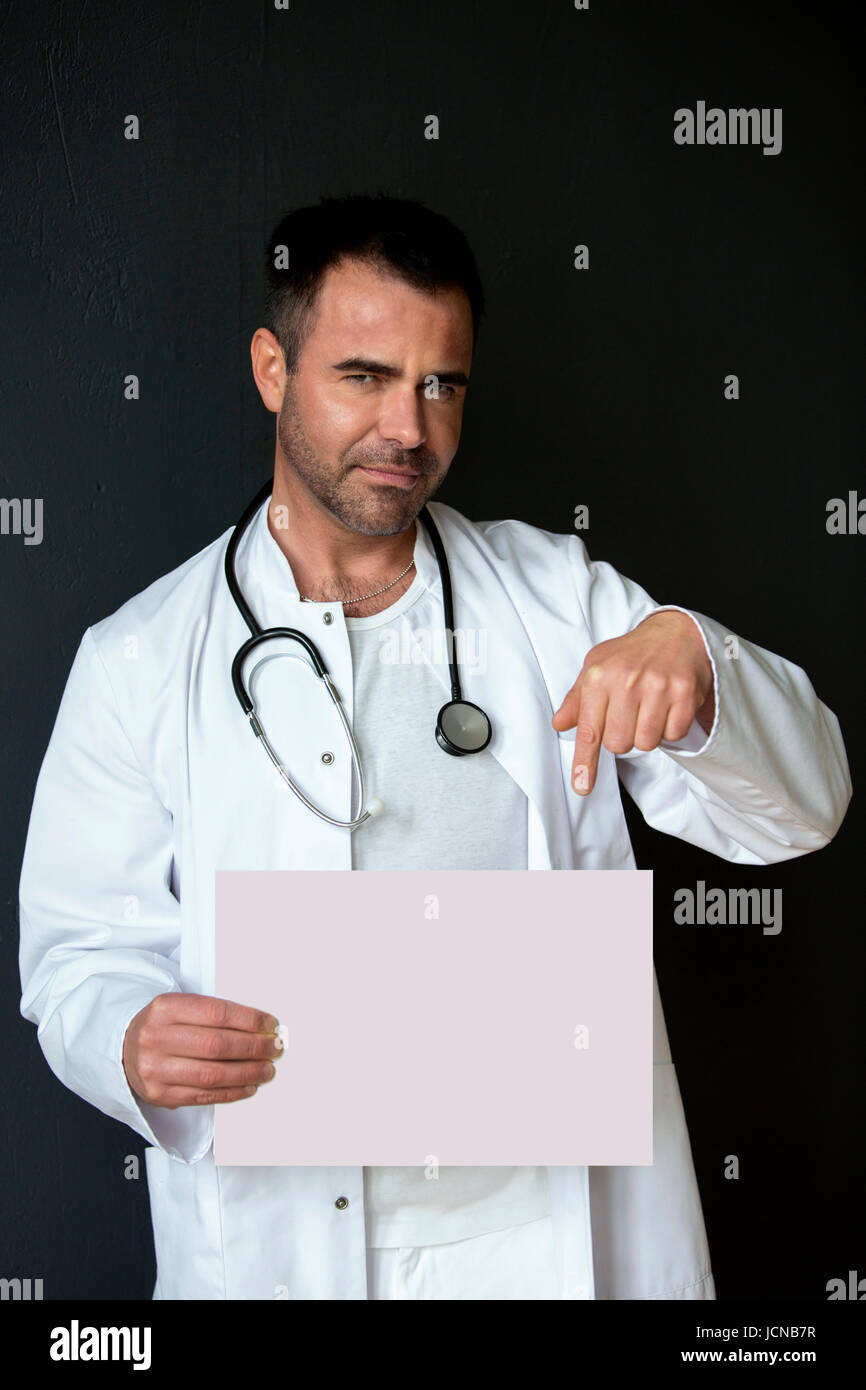 handsome doctor holding a blank sign with a warning look Stock Photo ...