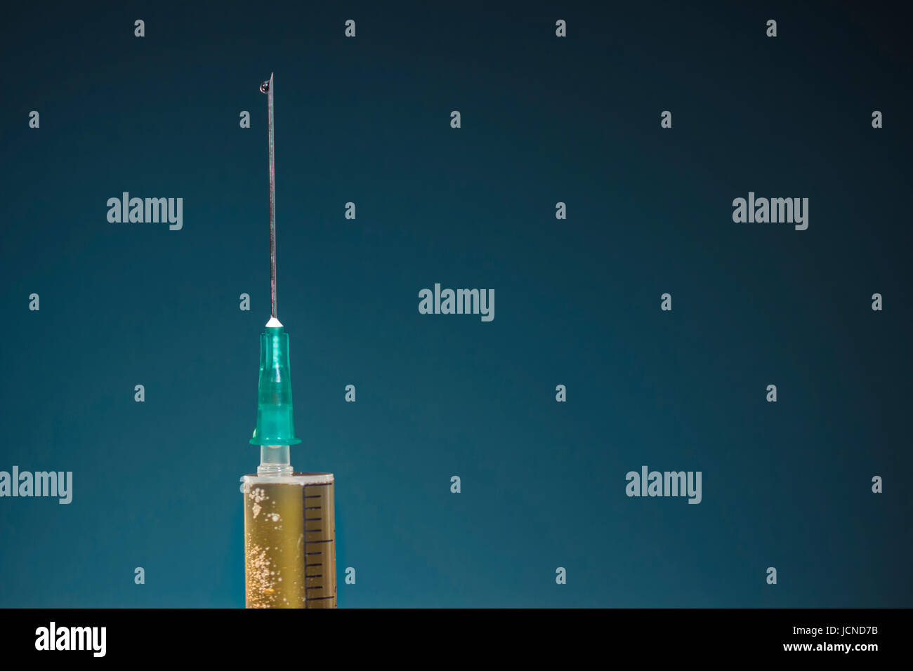 Hypodermic needle with a drop at its tip and the top of syringe with ...