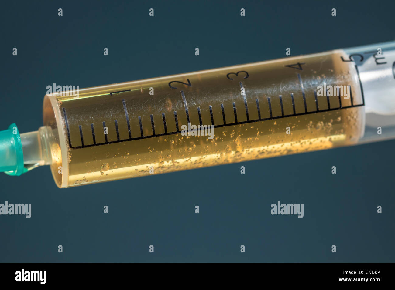Detail of syringe with a dark yellow drug inside Stock Photo - Alamy