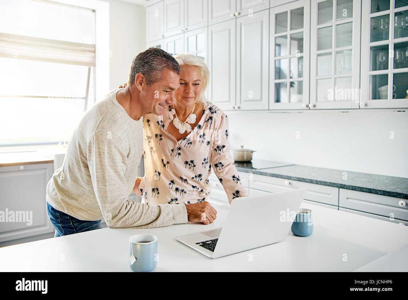 Two elderly people using a laptop computer at the kitchen Stock Photo ...