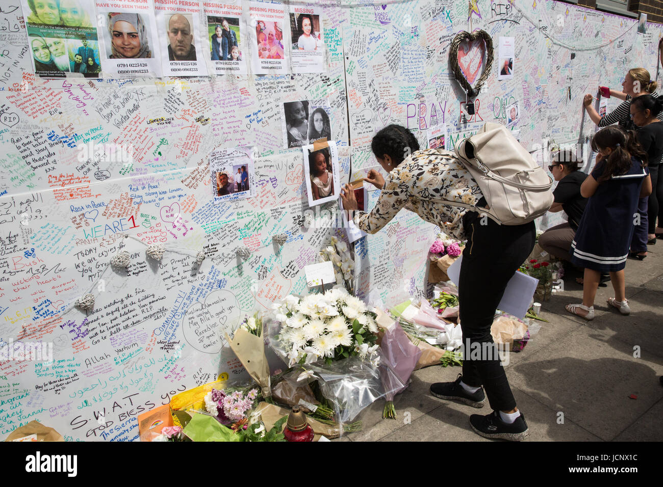 London, UK. 16th June, 2017. A woman fixes a missing person notice to ...
