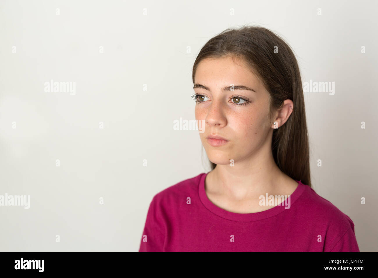 15 year old teenager portrait with serious face on a white background ...
