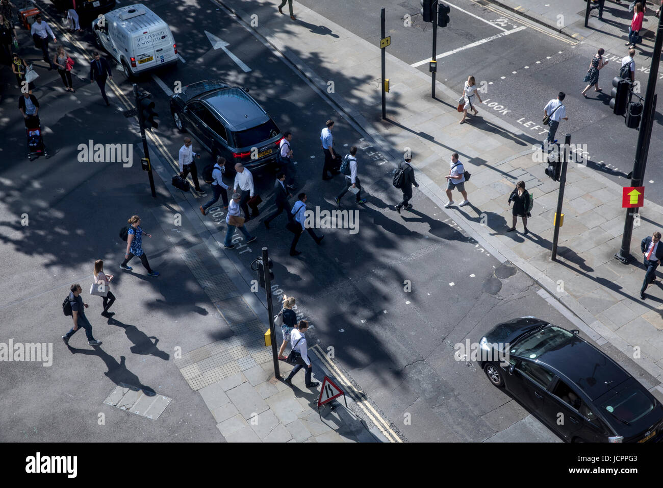 pedestrians crossing road in City of London during morning rush hour ...