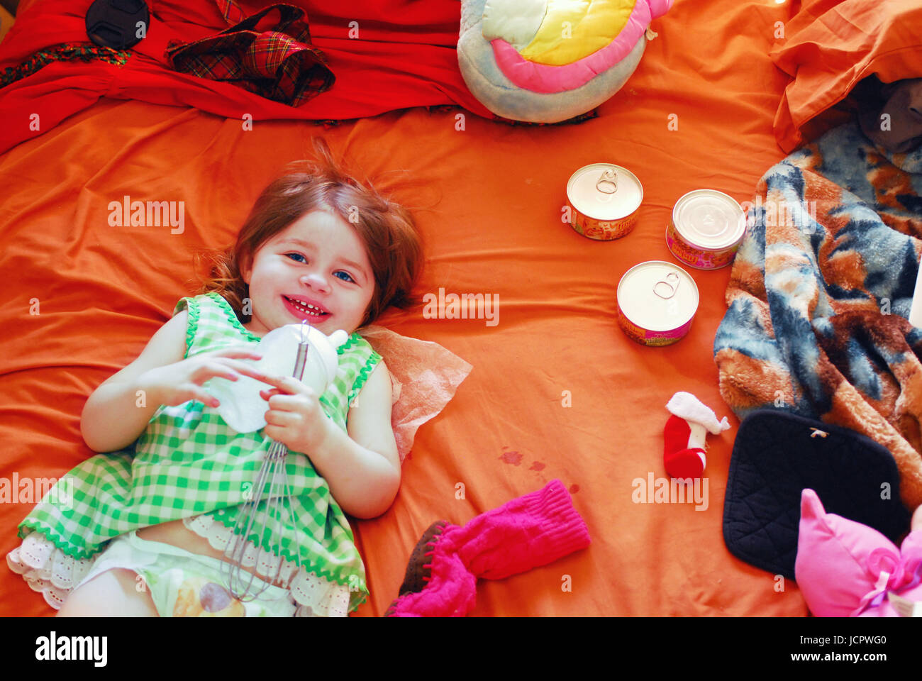 toddler lying on messy bed with assorted objects Stock Photo - Alamy