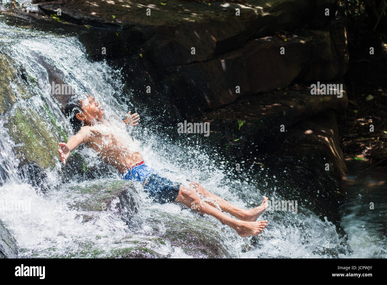 Boy playing waterfall Flowing from the jungle Stock Photo - Alamy