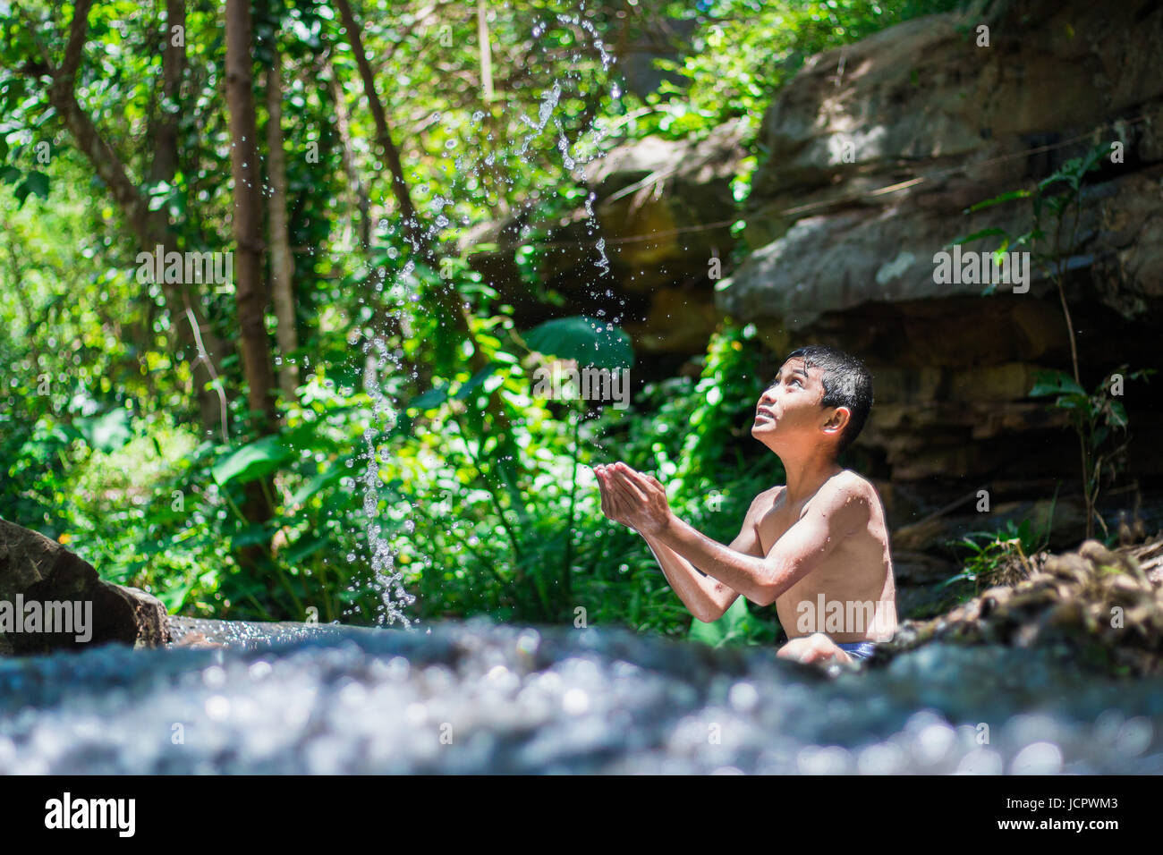 Boy playing waterfall Flowing from the jungle Stock Photo - Alamy