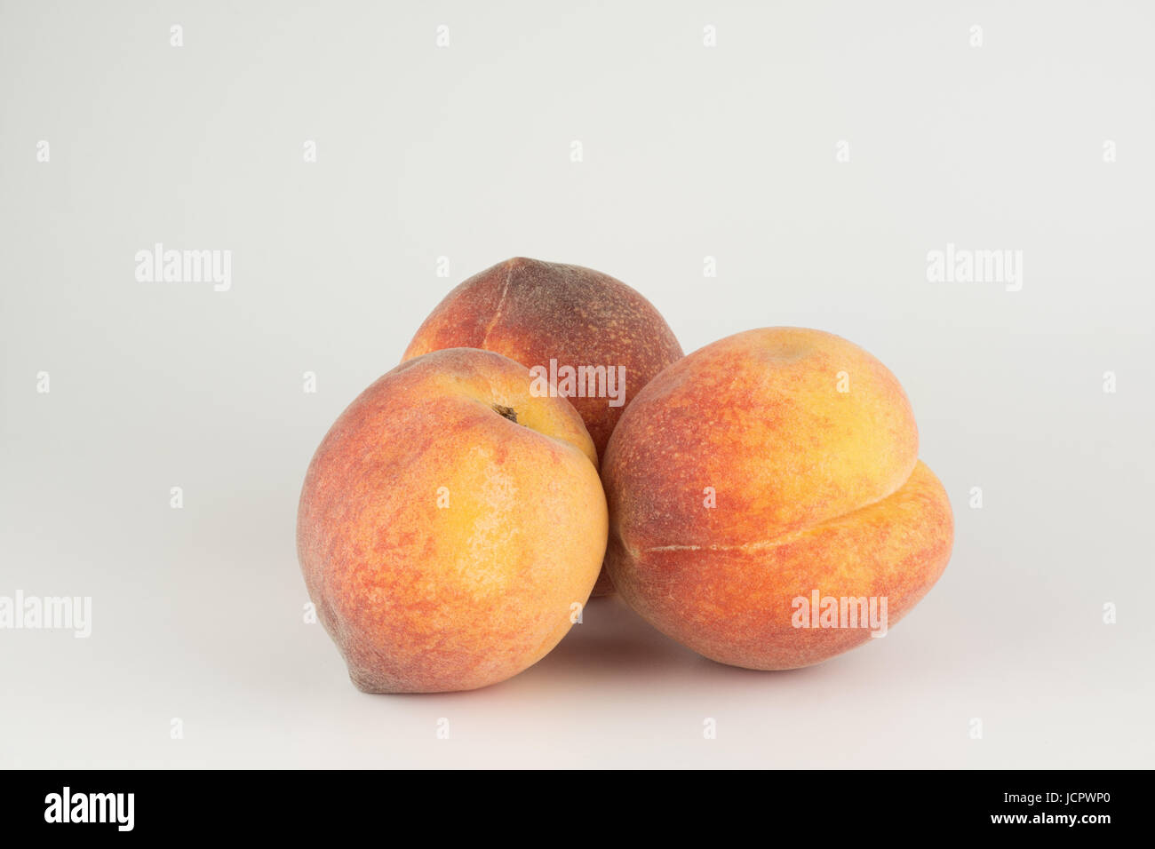 Three large ripe peaches on a white background Stock Photo - Alamy