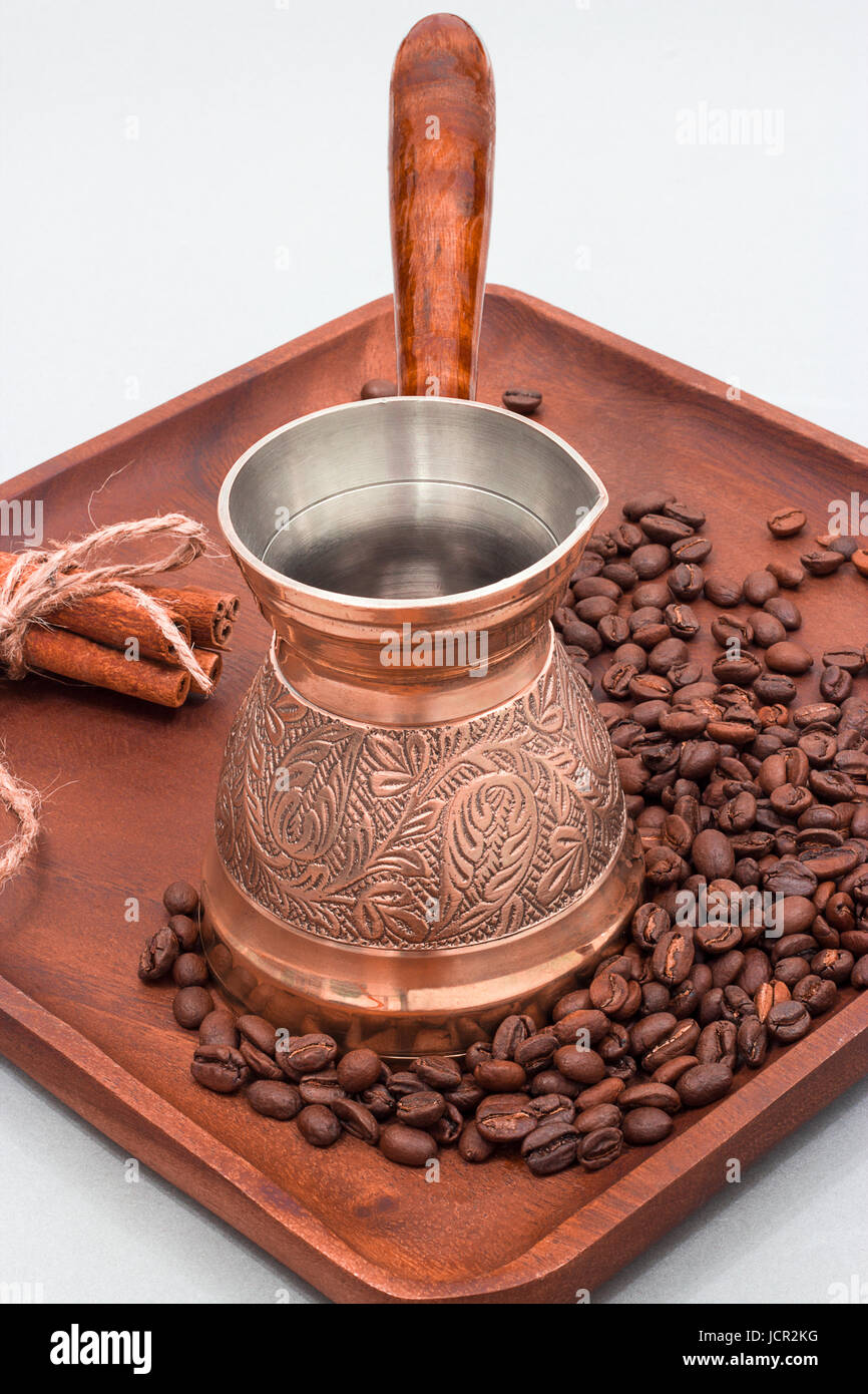 Copper coffee pot with coffee beans and cinnamon sticks. On a wooden ...