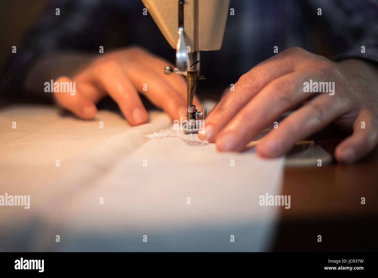 Sewing machine, sewing process, women's hands holding a cloth to sew ...