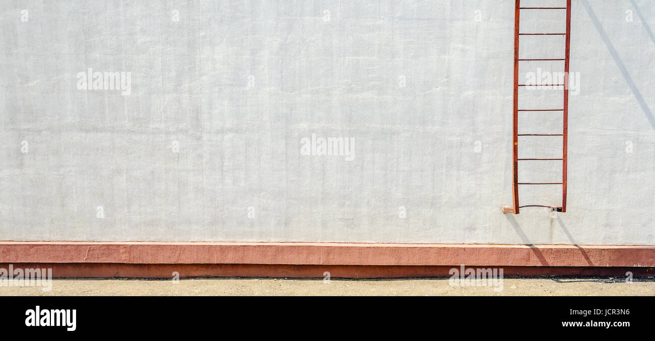 Element of building facade with fire escape. White plaster wall texture ...