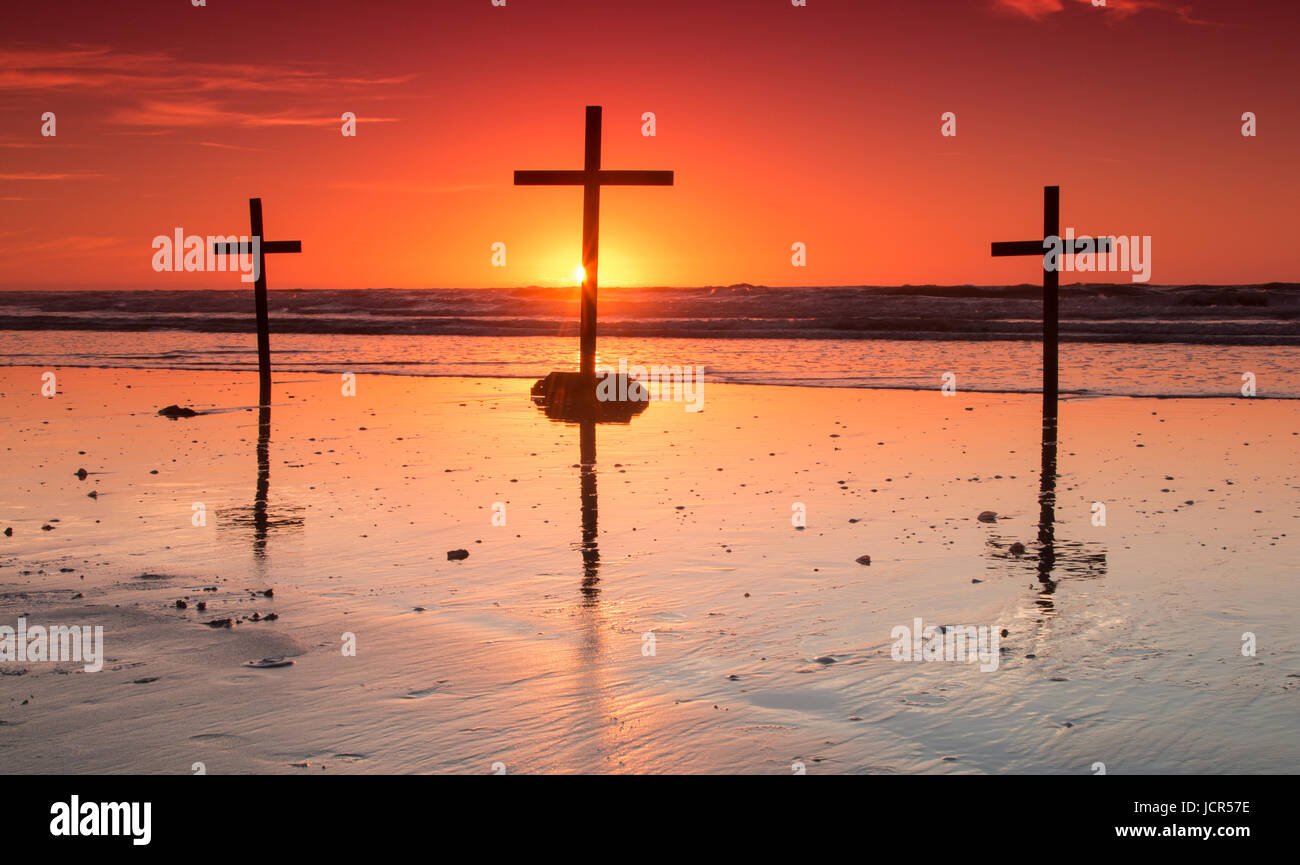 Three crosses at sundown on a wonderful beach, with the sun setting ...