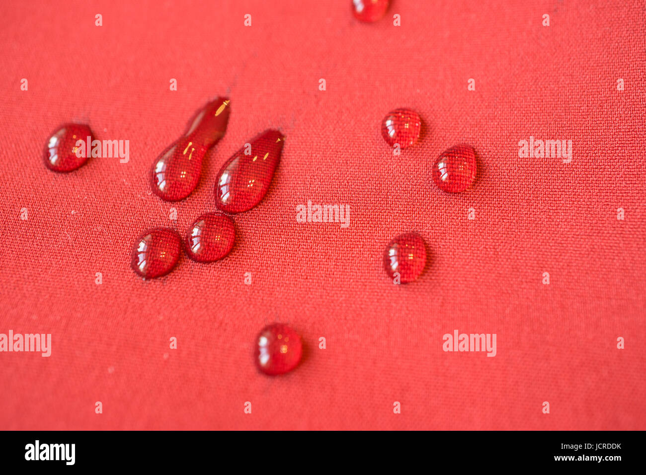large water drops on red waterproof membrane apparel close up of ...