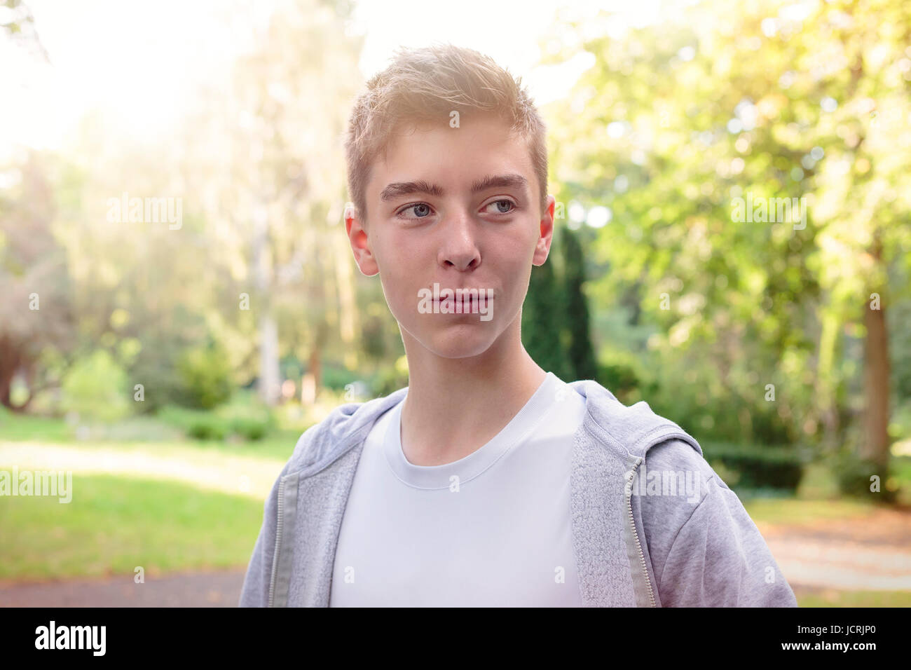 portrait of a smiling young man standing in a sun-washed landscape ...