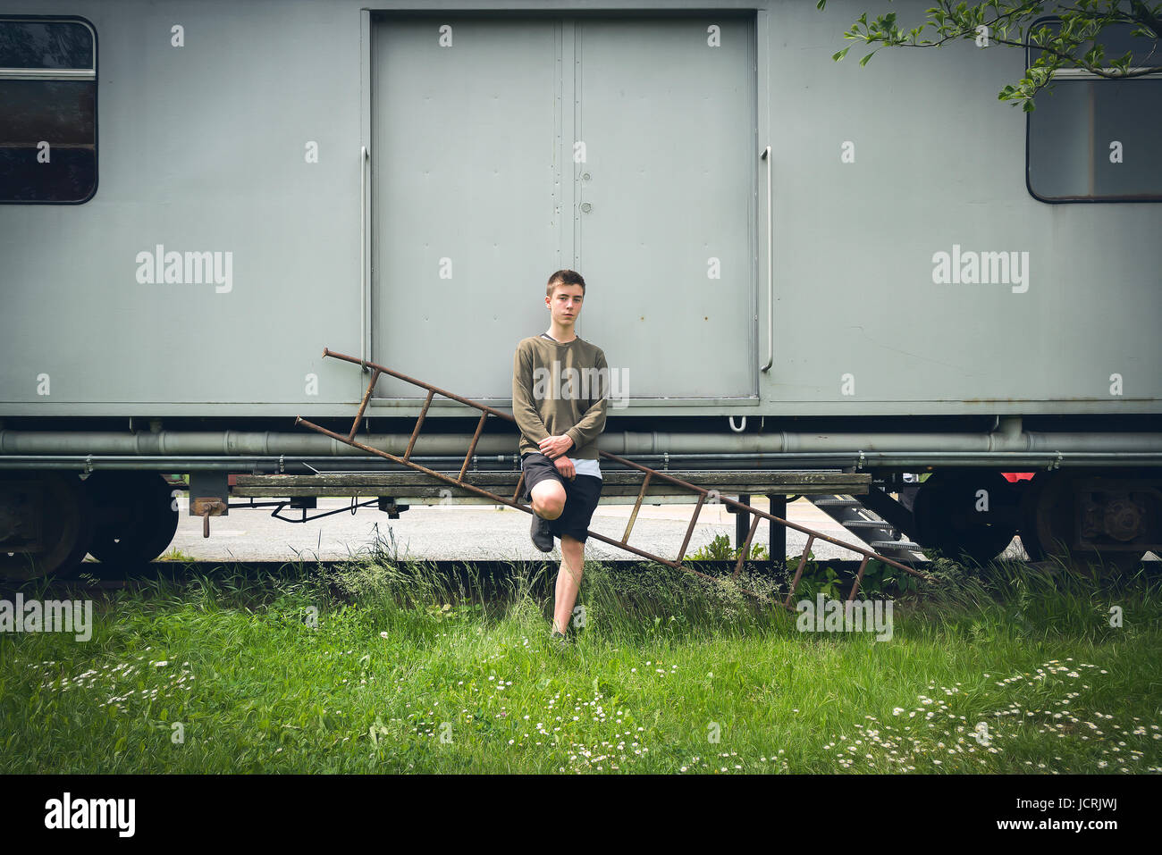 young man leaning against an old rail car Stock Photo - Alamy