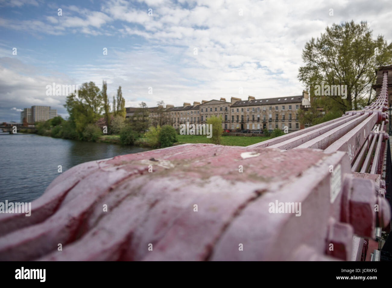 red bridge railing with river and town Stock Photo - Alamy