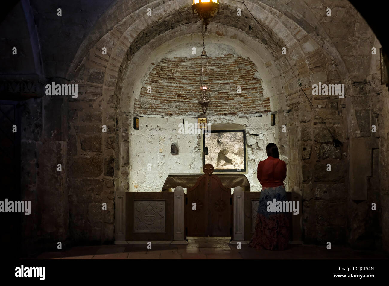 A Christian worshiper prays inside the Greek Orthodox Chapel of Adam in ...