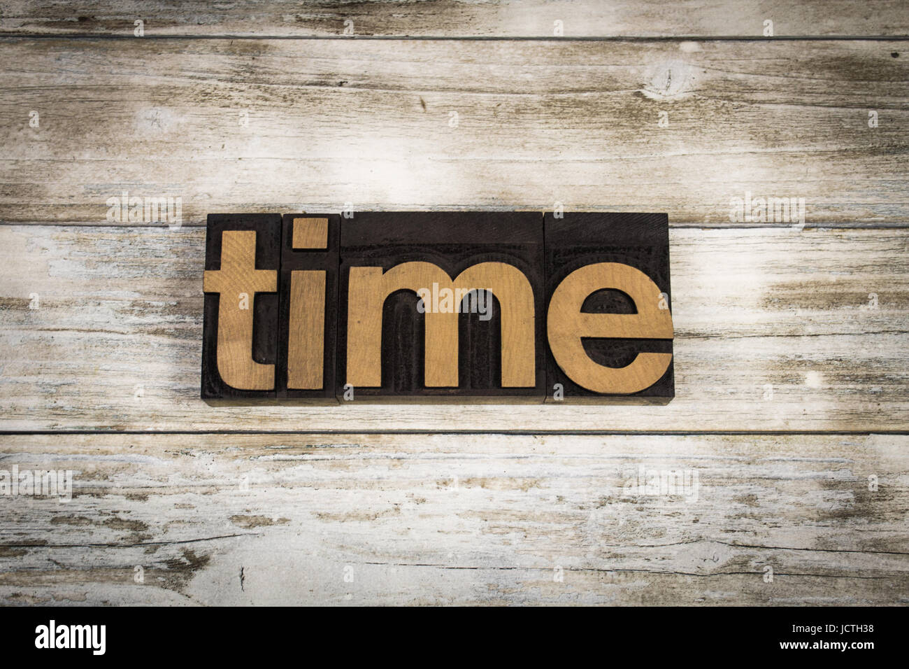 The word "time" written in wooden letterpress type on a white washed ...