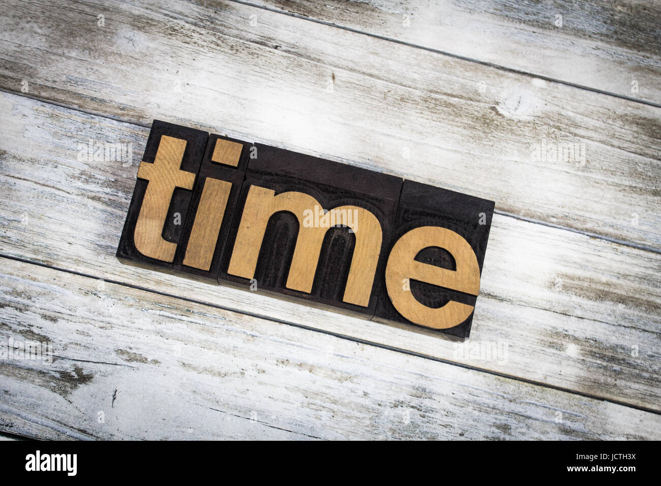 The word "time" written in wooden letterpress type on a white washed ...