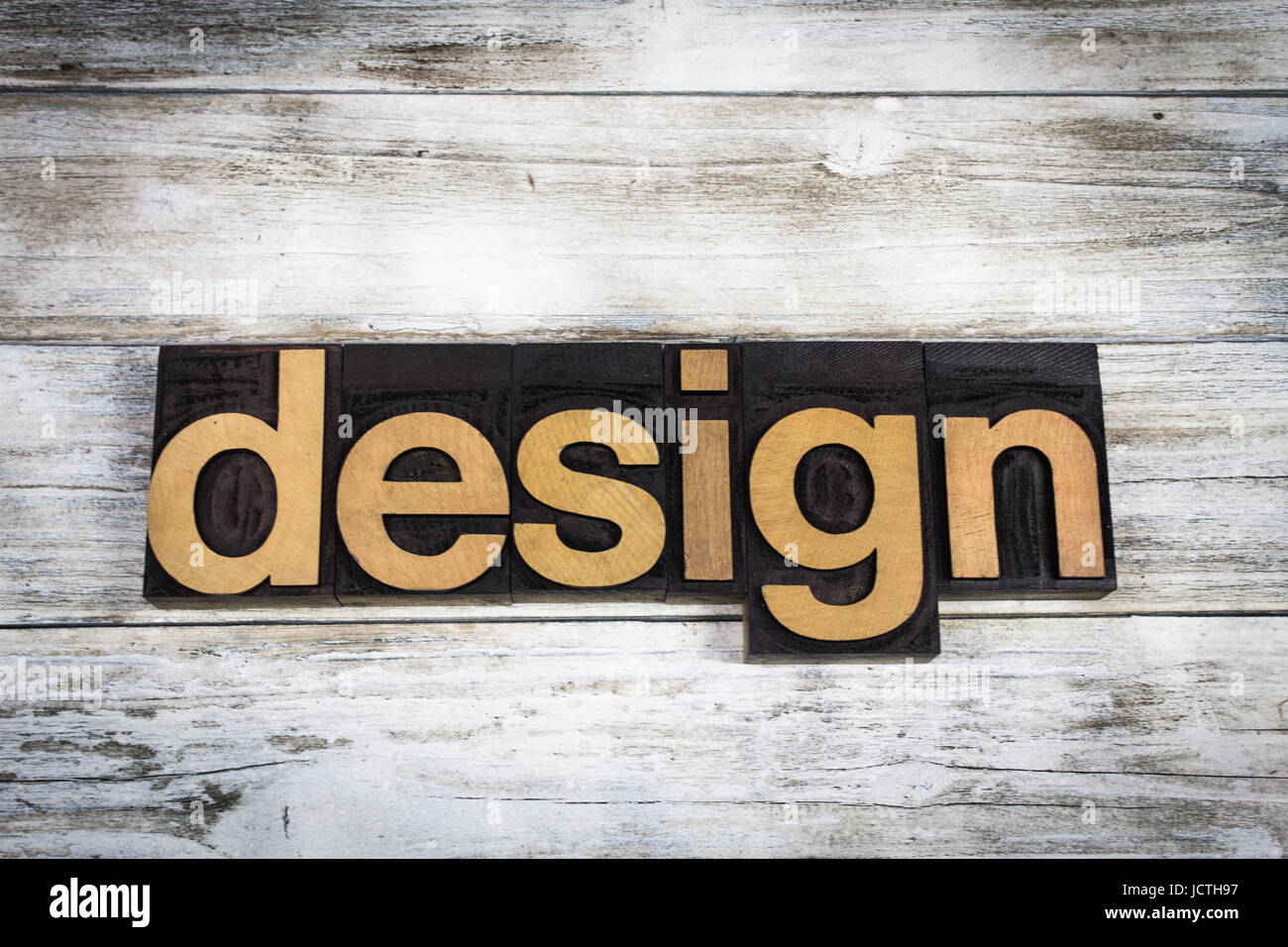 The word "design" written in wooden letterpress type on a white washed ...