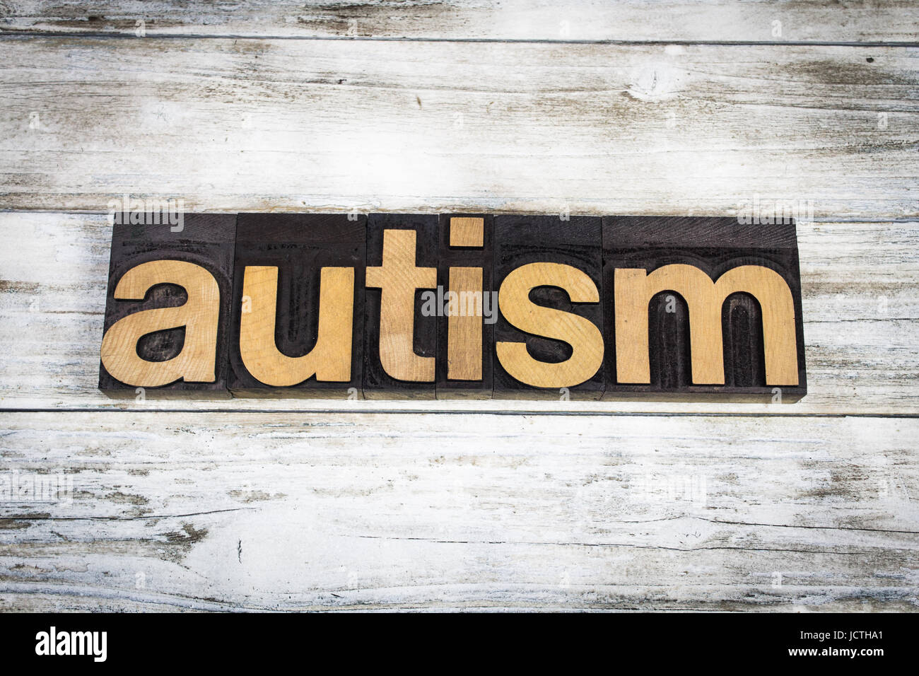 The word "autism" written in wooden letterpress type on a white washed ...