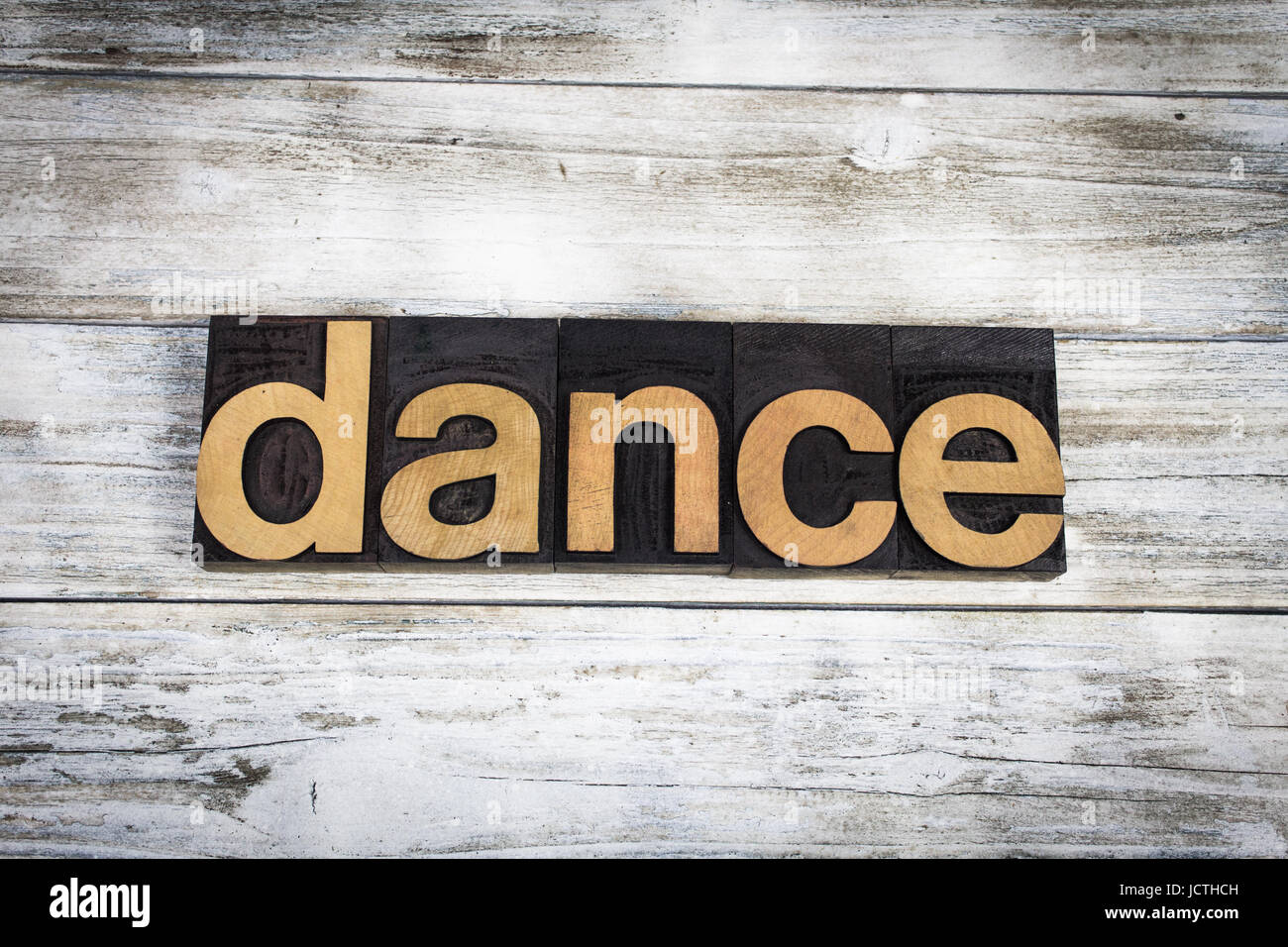 The word "dance" written in wooden letterpress type on a white washed ...
