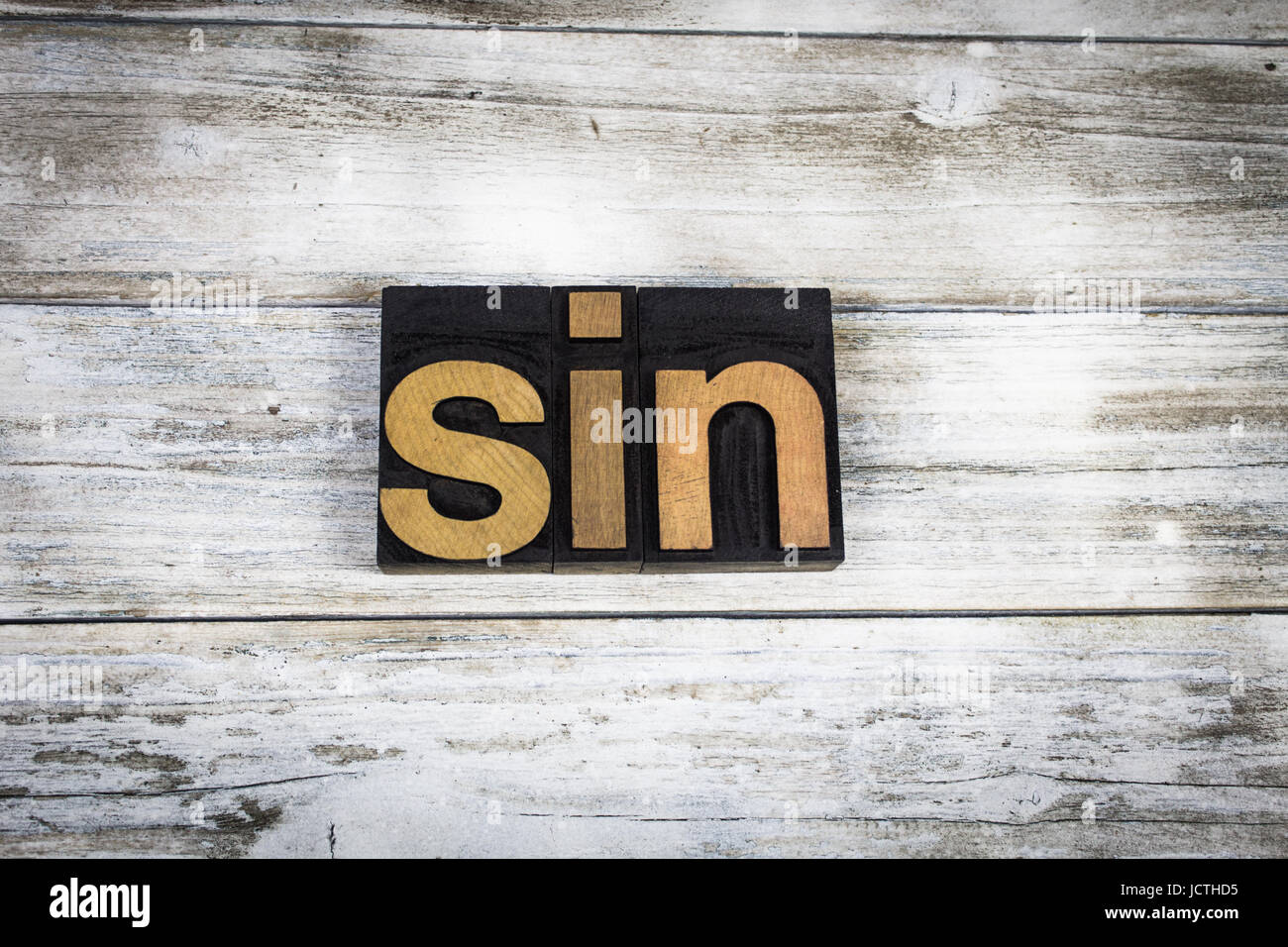 The word "Sin" written in wooden letterpress type on a white washed old ...
