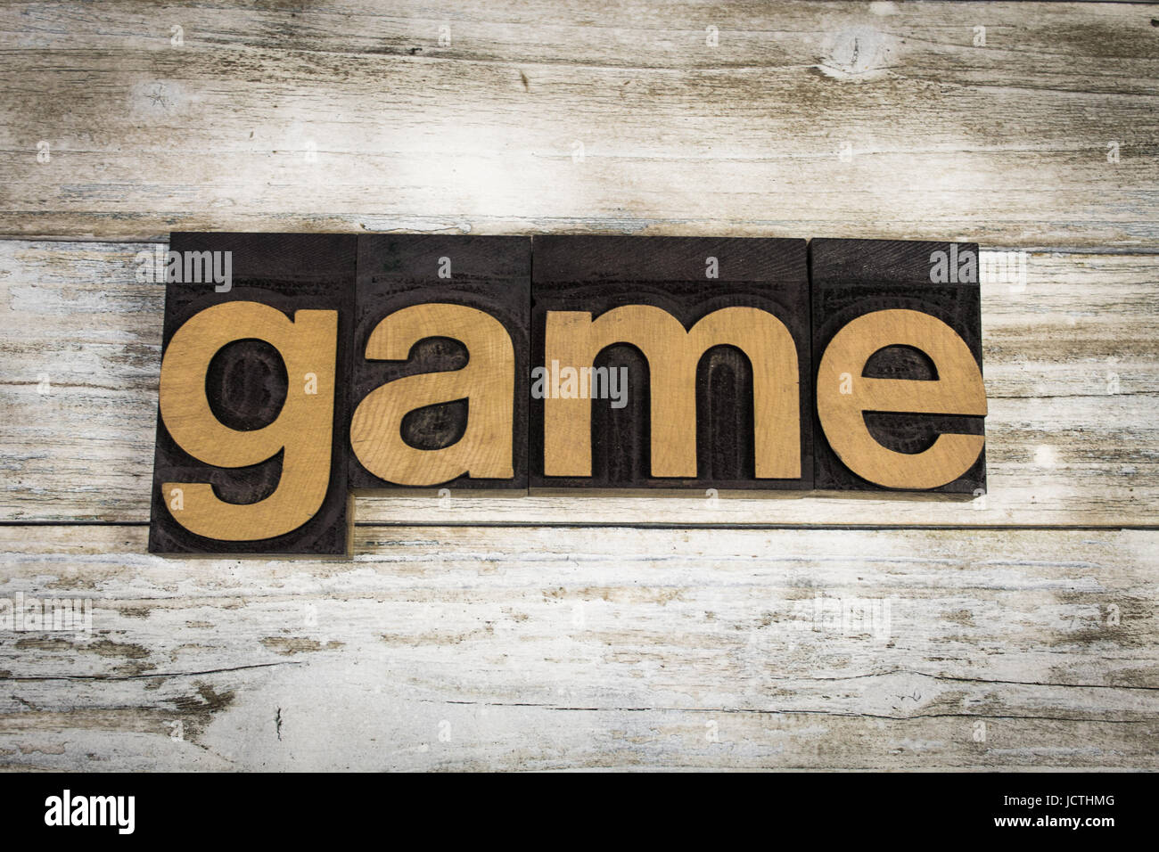 The word "game" written in wooden letterpress type on a white washed ...