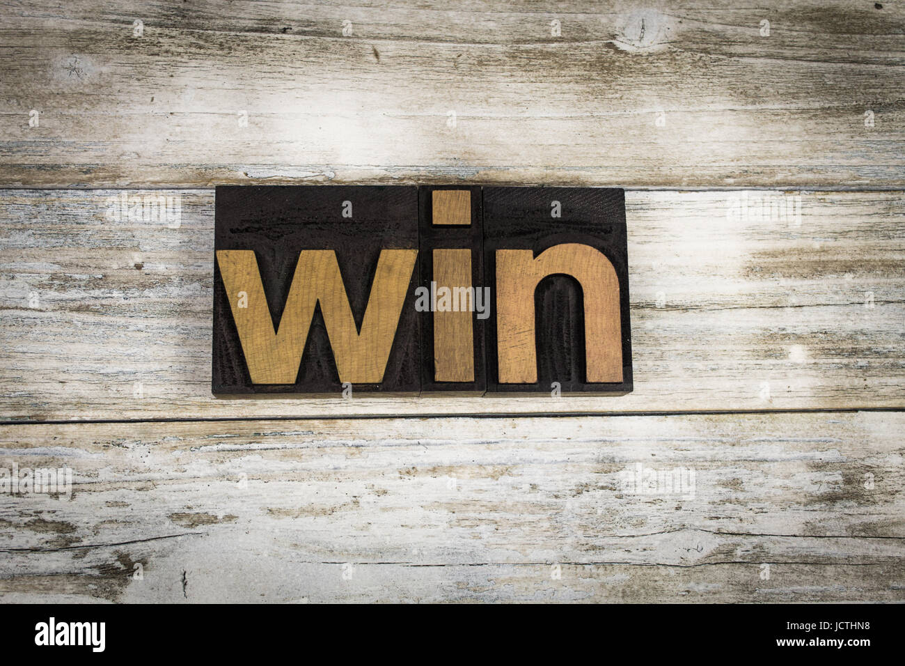 The word "win" written in wooden letterpress type on a white washed old ...