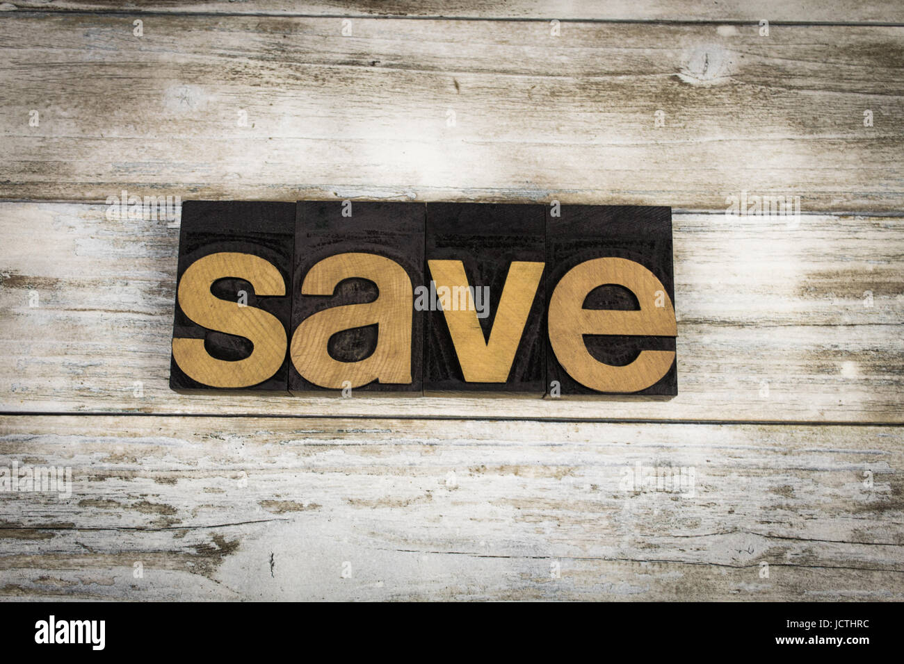 The word "save" written in wooden letterpress type on a white washed ...