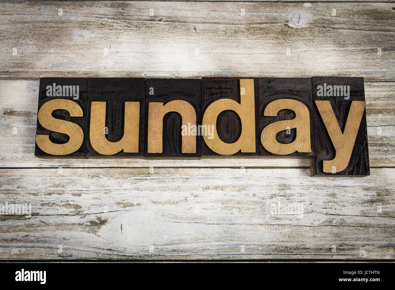 The word "Sunday" written in wooden letterpress type on a white washed ...