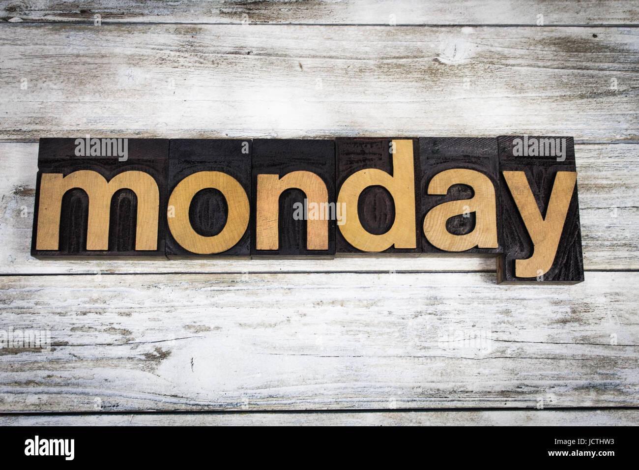 The word "Monday" written in wooden letterpress type on a white washed ...