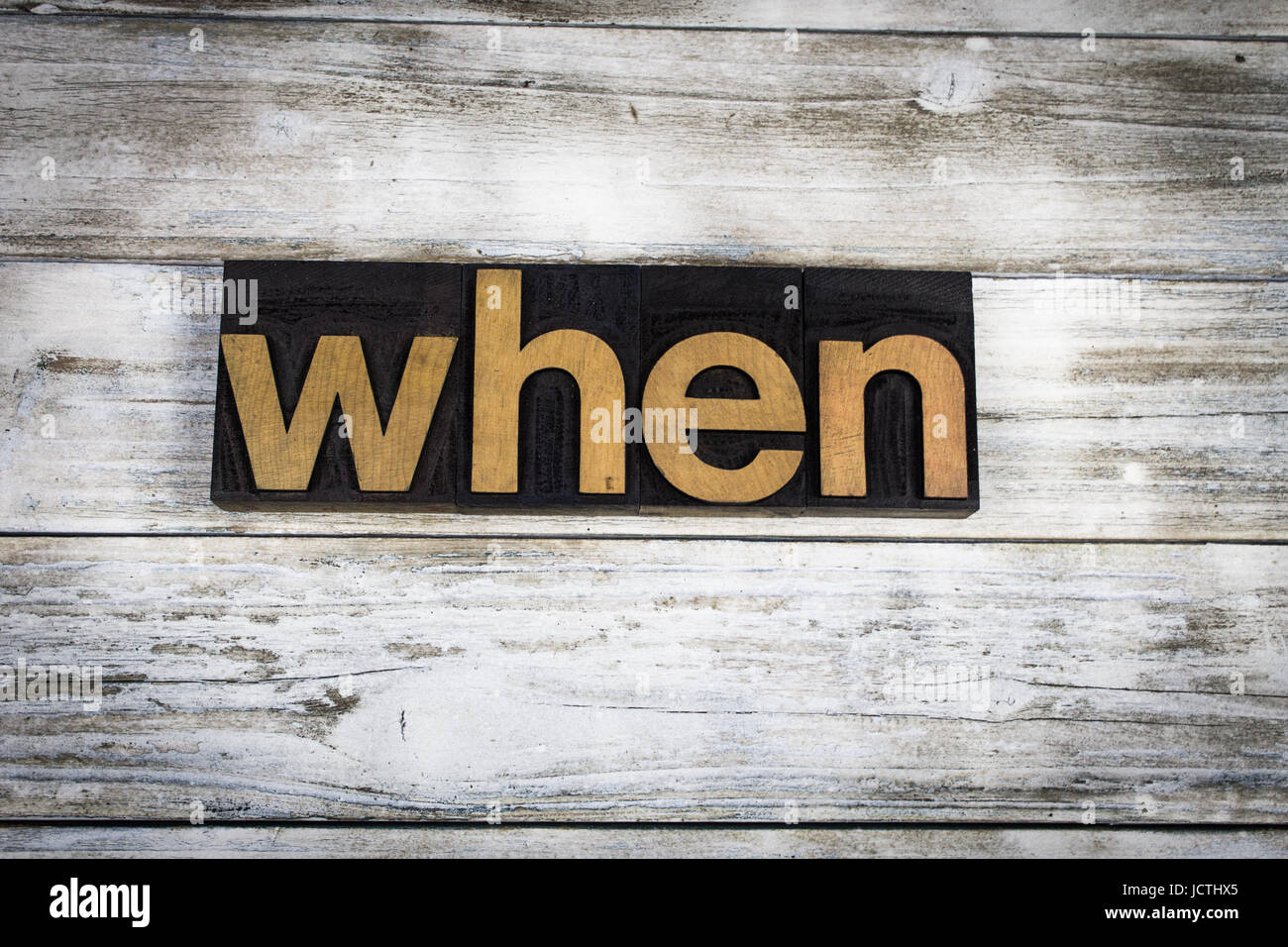 The word "when" written in wooden letterpress type on a white washed ...
