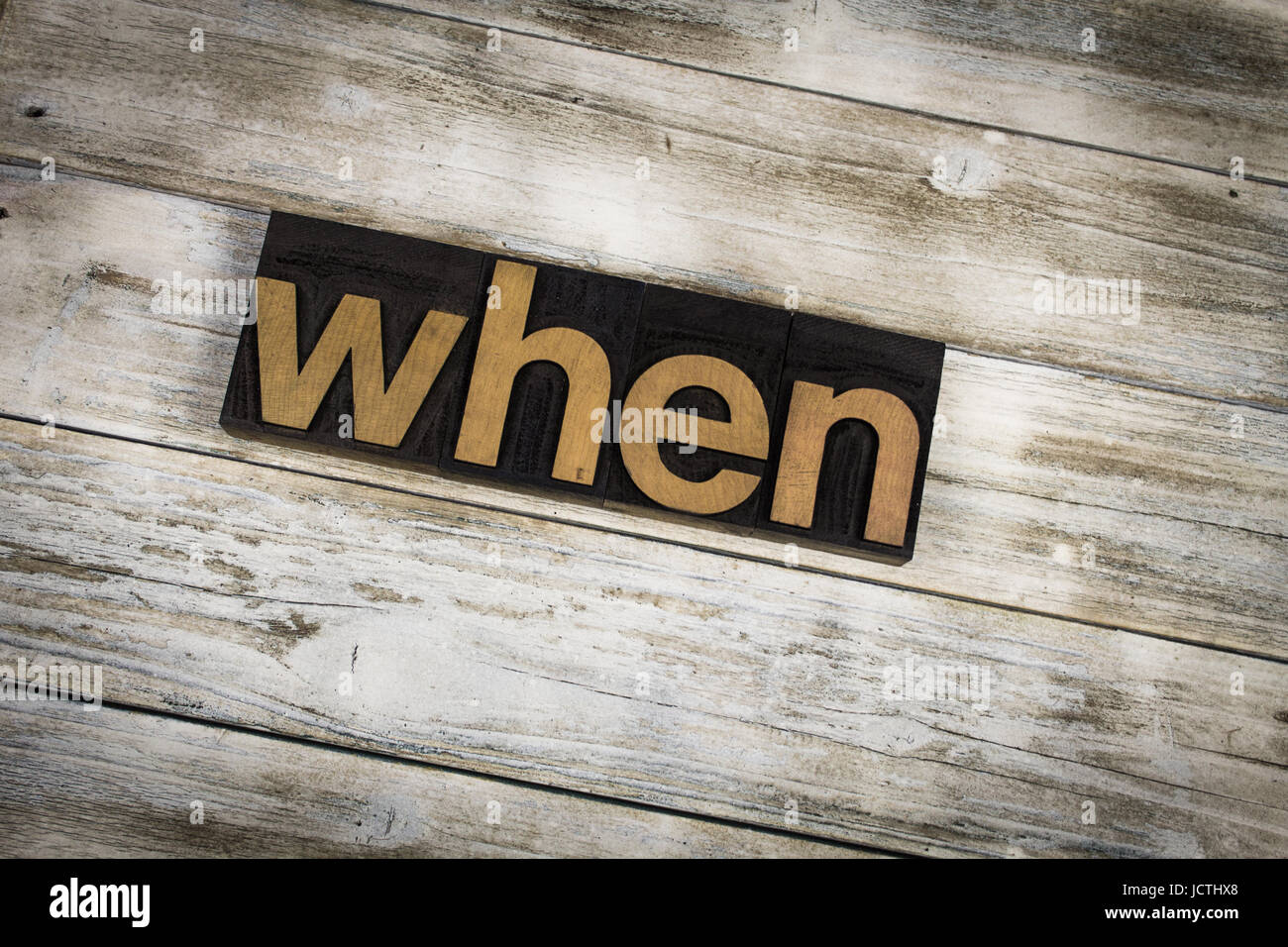 The word "when" written in wooden letterpress type on a white washed ...