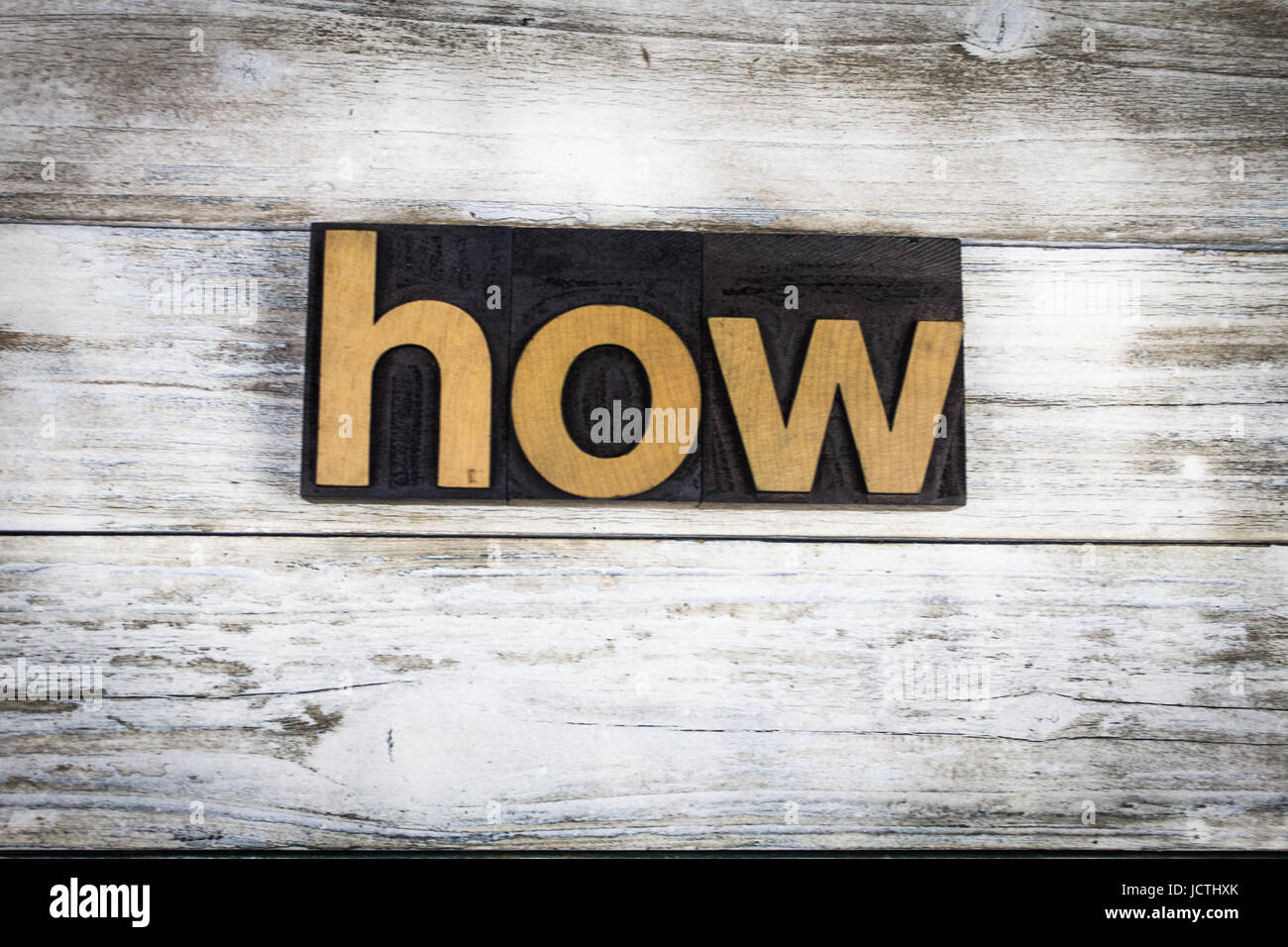 The word "how" written in wooden letterpress type on a white washed old ...