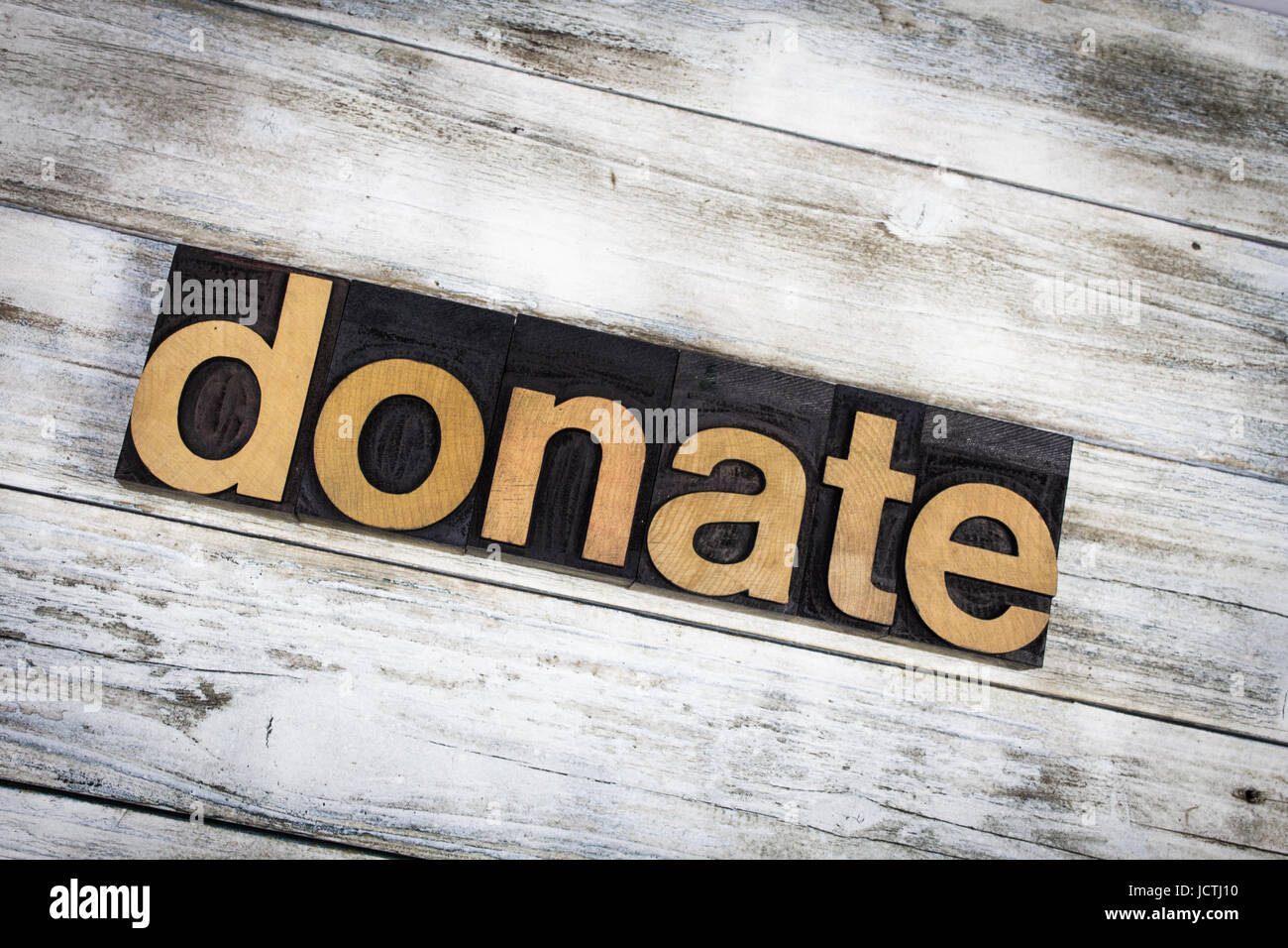 The word "donate" written in wooden letterpress type on a white washed ...