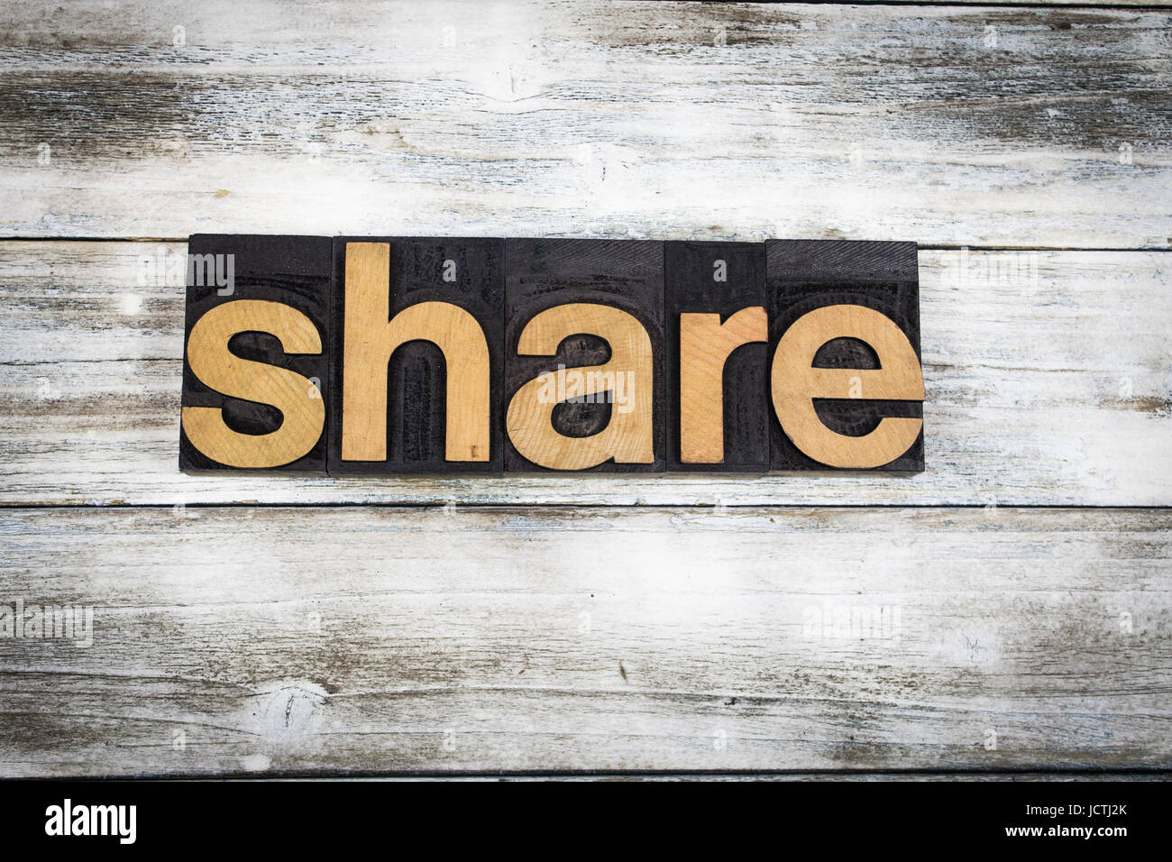 The word "share" written in wooden letterpress type on a white washed ...