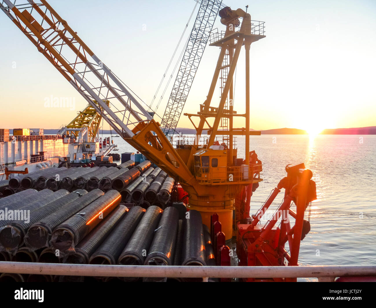 The deck lay barge. Pipes and Lifting cranes on the ship. Equipment for ...