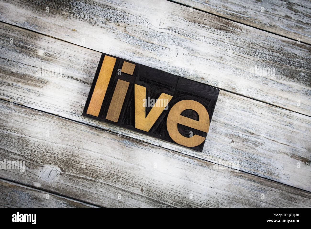 The word "live" written in wooden letterpress type on a white washed ...