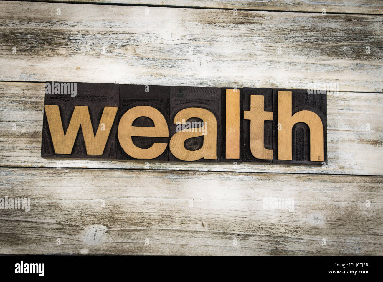 The word "wealth" written in wooden letterpress type on a white washed ...