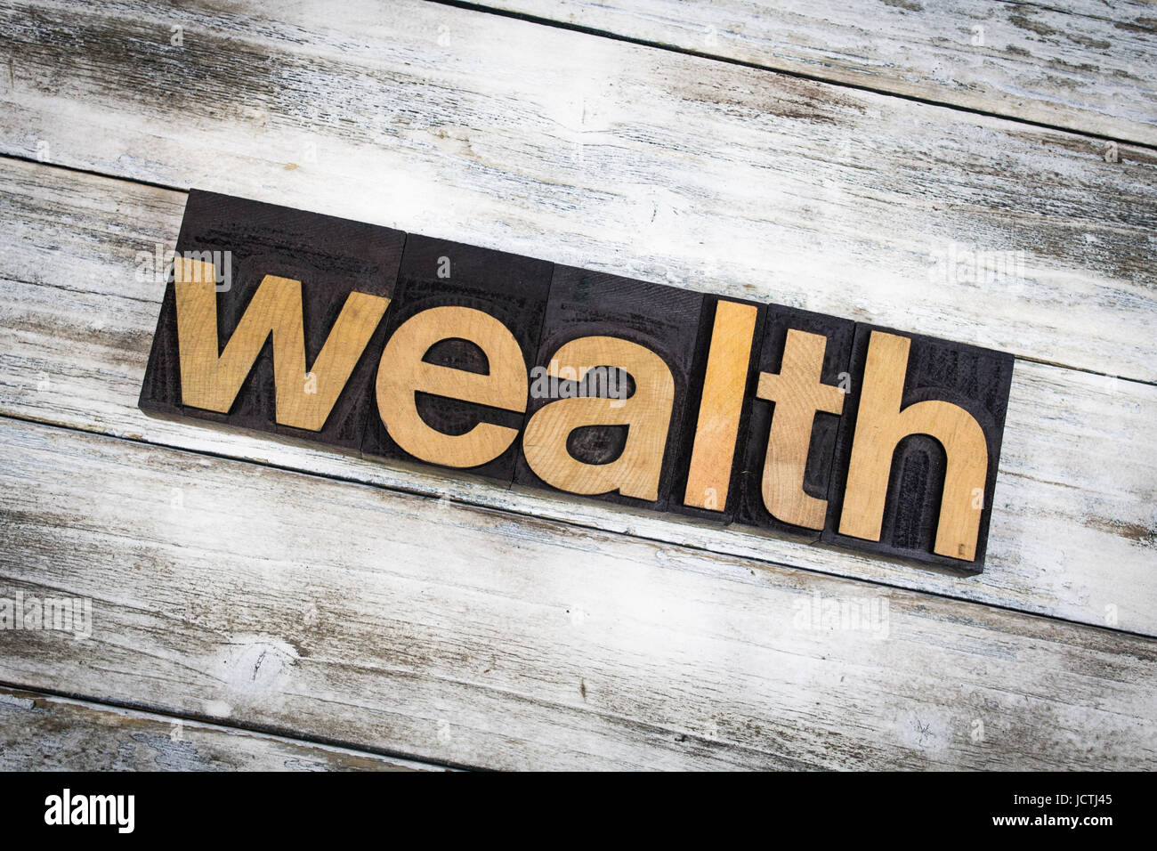 The word "wealth" written in wooden letterpress type on a white washed ...