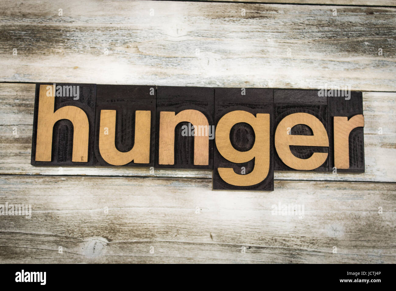 The word "hunger" written in wooden letterpress type on a white washed ...