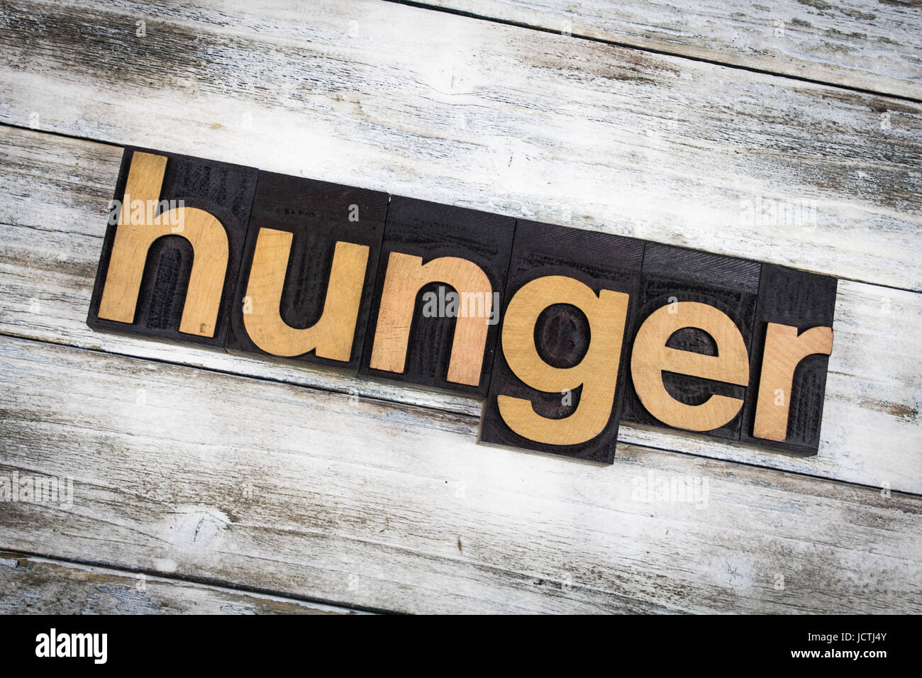 The word "hunger" written in wooden letterpress type on a white washed ...