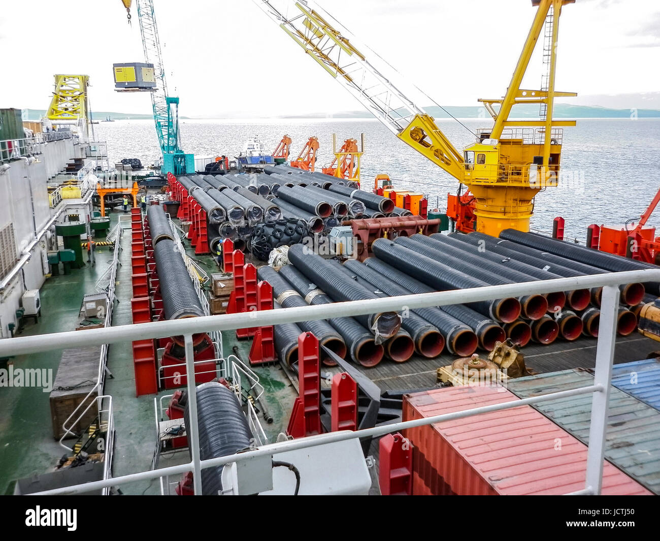 The deck lay barge. Pipes and Lifting cranes on the ship. Equipment for ...