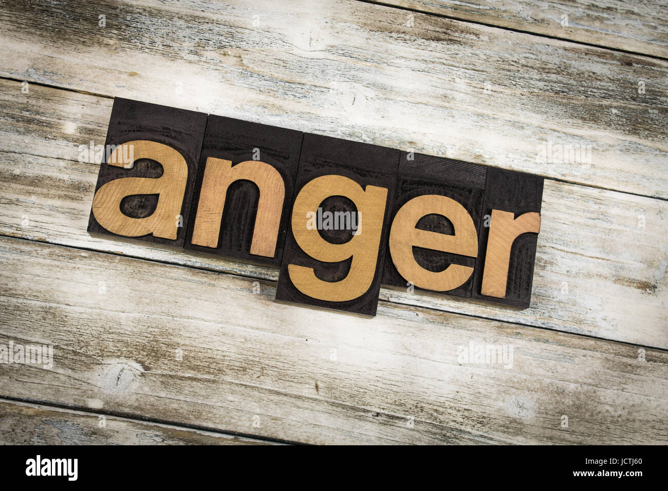 The word "anger" written in wooden letterpress type on a white washed ...