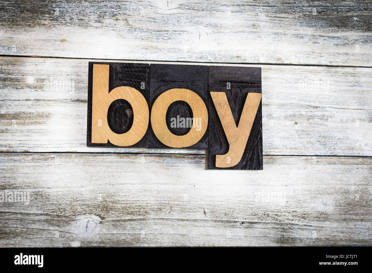 The word "boy" written in wooden letterpress type on a white washed old ...