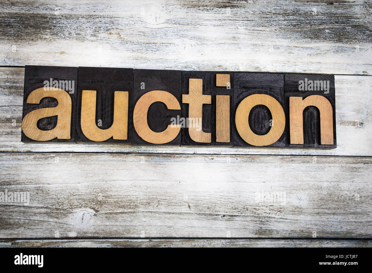 The word "auction" written in wooden letterpress type on a white washed ...