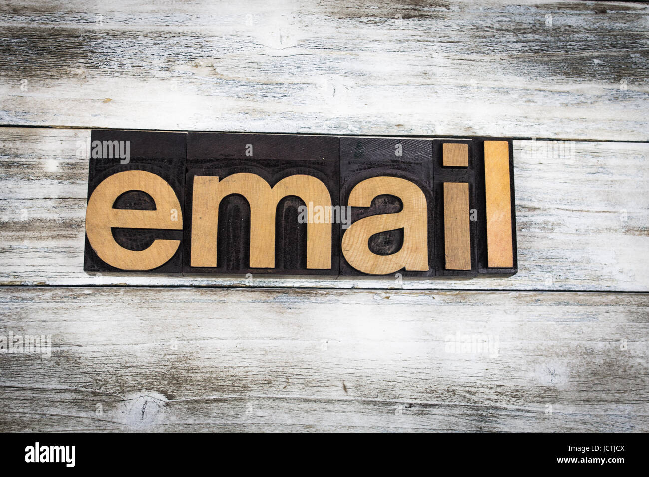 The word "email" written in wooden letterpress type on a white washed ...