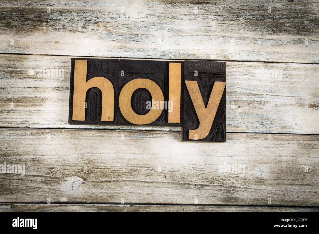 The word "holy" written in wooden letterpress type on a white washed ...